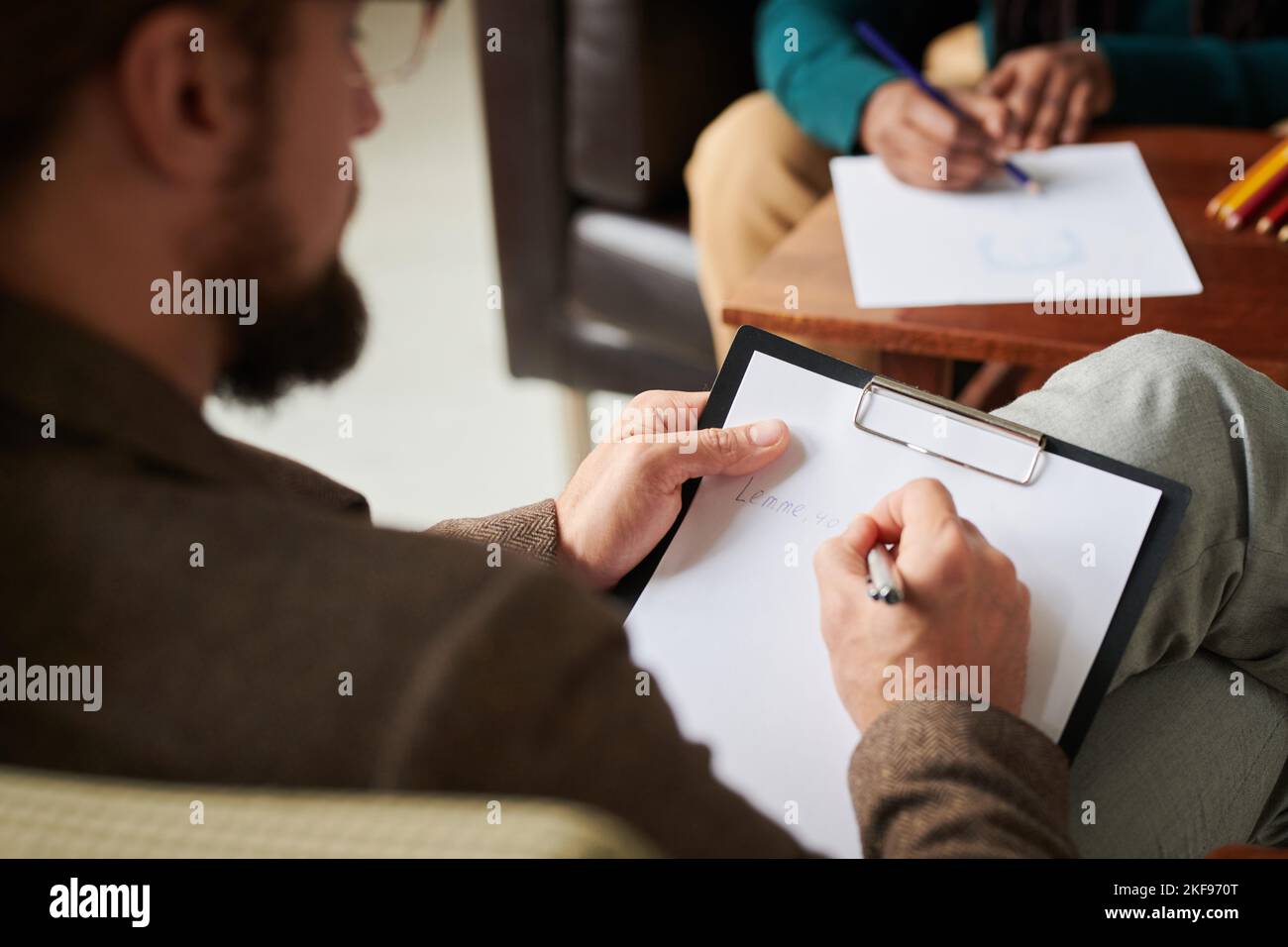 Close-up of psychologist making notes in document during art therapy ...