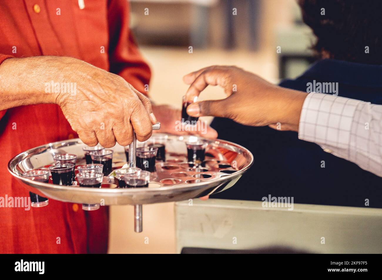 The person treats the red wine with small glasses to churchgoers to ...