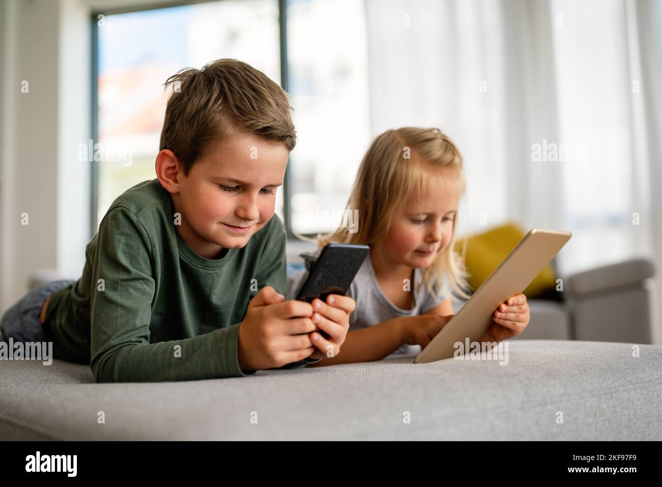Little kids holding smartphone, tablet playing mobile game online, child and gadget concept ...