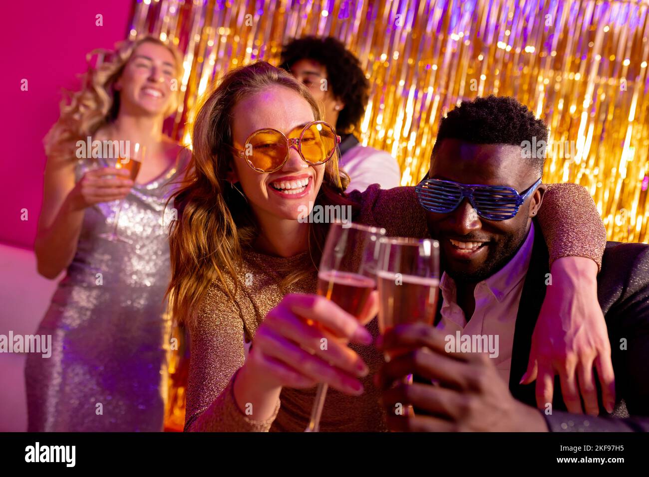 Happy diverse couple dancing and toasting with champagne at a nightclub ...
