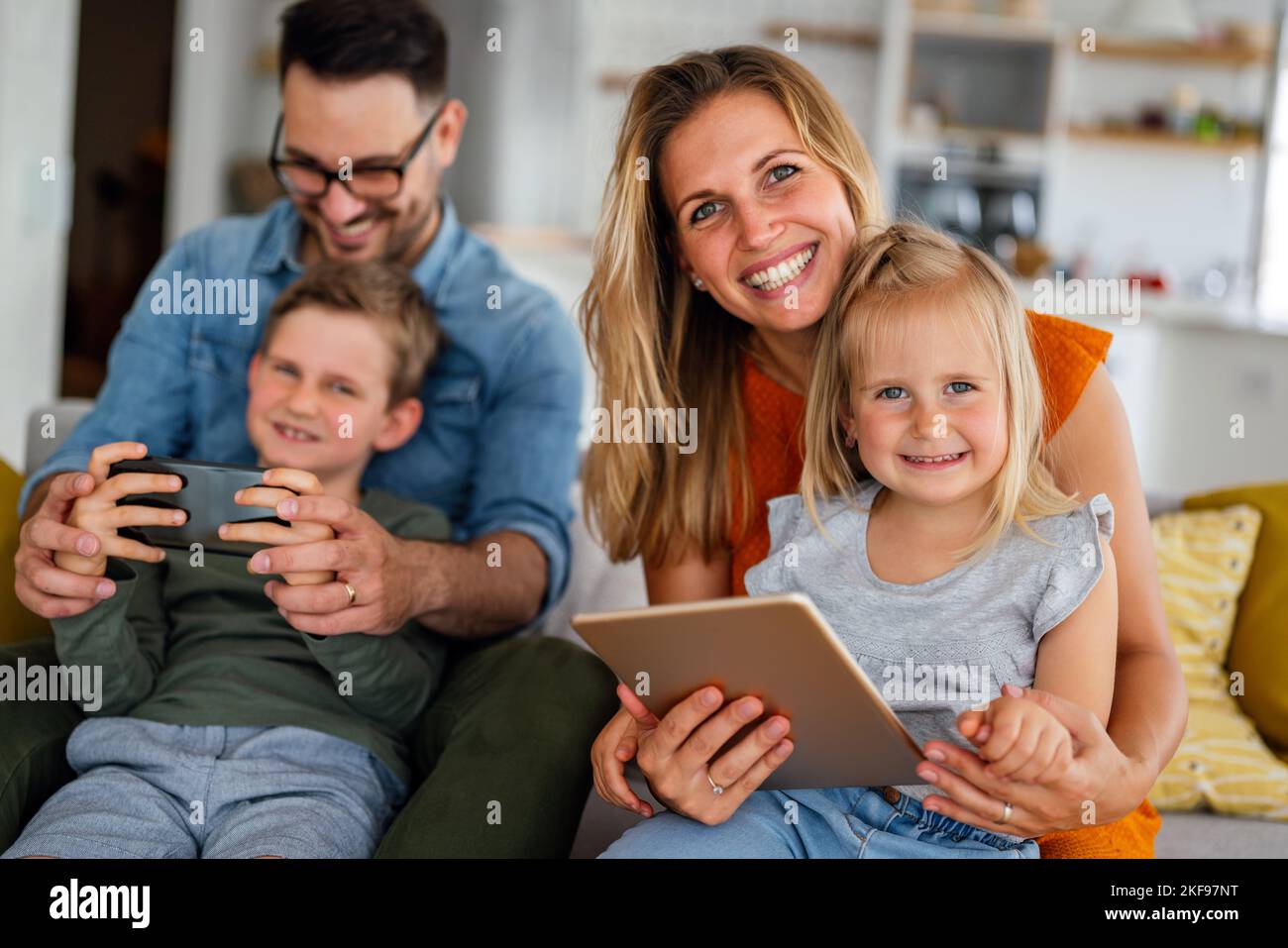 Happy family spending time at home with digital devices together ...