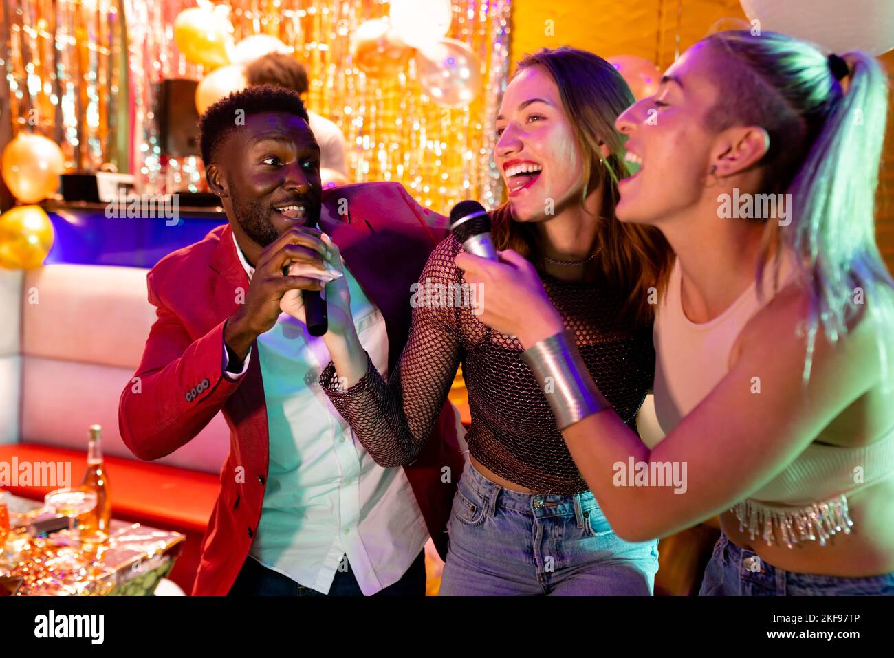 Three Diverse Male And Female Friends Having Fun Singing Karaoke At A