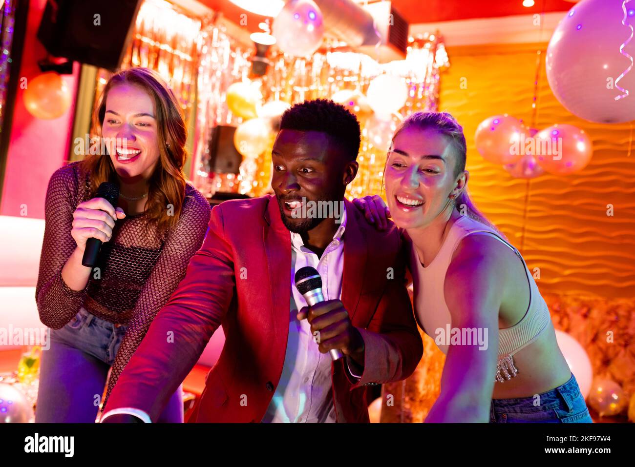 Three Diverse Male And Female Friends Having Fun Singing Karaoke At A