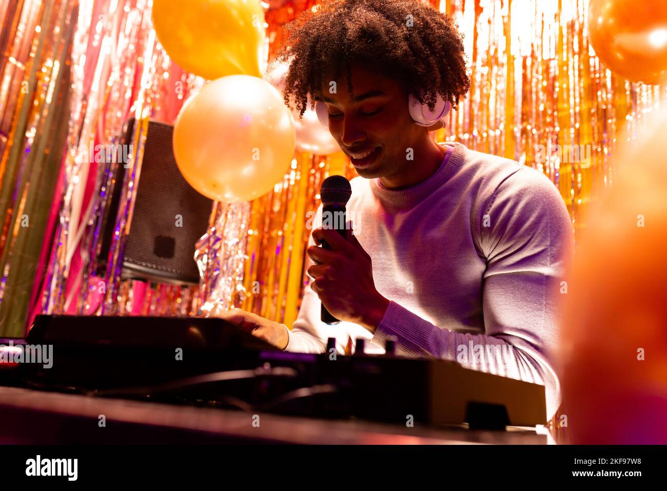 Smiling african american dj in headphones playing music at a nightclub ...