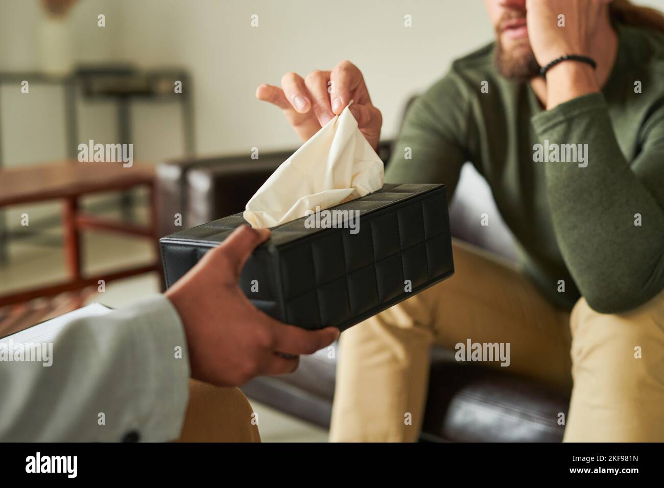 Close-up of psychologist giving box with tissues to man during ...