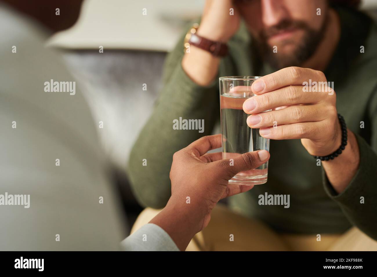 Close-up of depressed patient drinking water giving by psychologist ...
