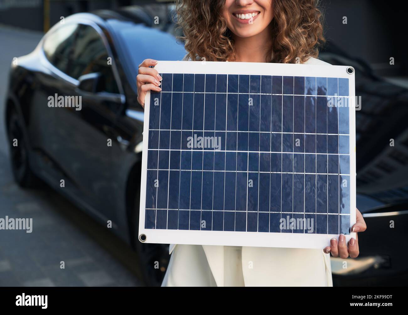 Cropped view of smiling girl holding solar panel on background of black ...