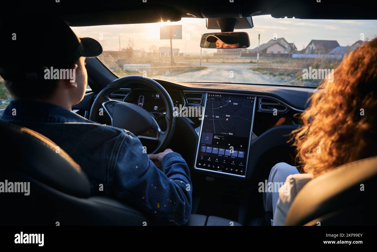 Rear view inside the car. Driver and passenger travelling by electric ...