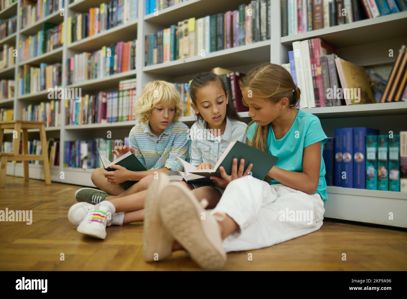 Group of kids reading while sitting on the floor in the library Stock ...