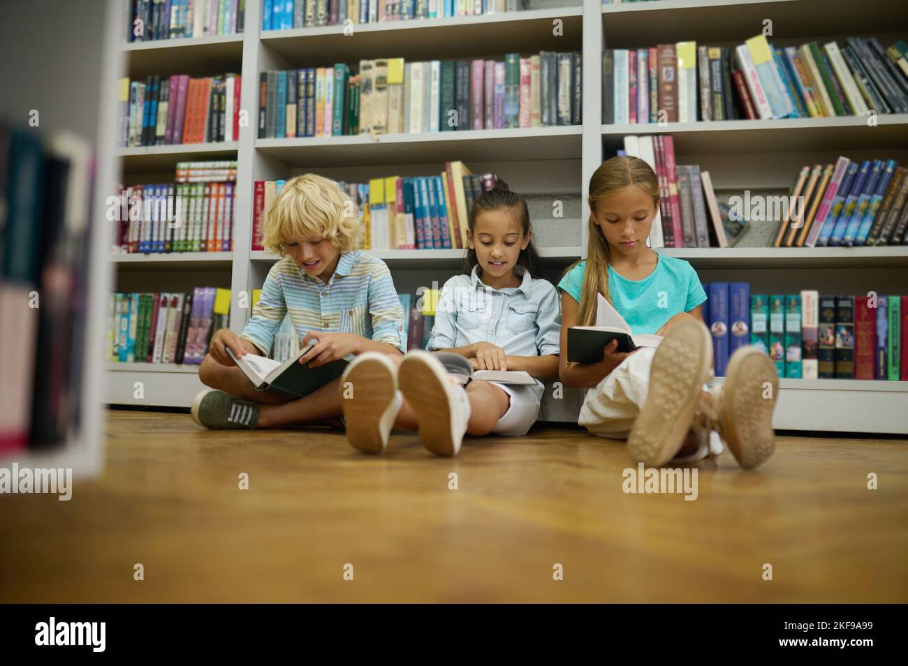 Group of kids reading while sitting on the floor in the library Stock ...