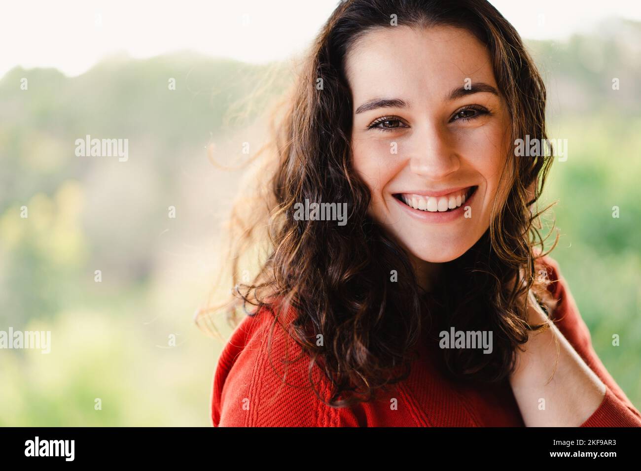 Young happy beautiful brunette woman smiling to camera and holding hair ...