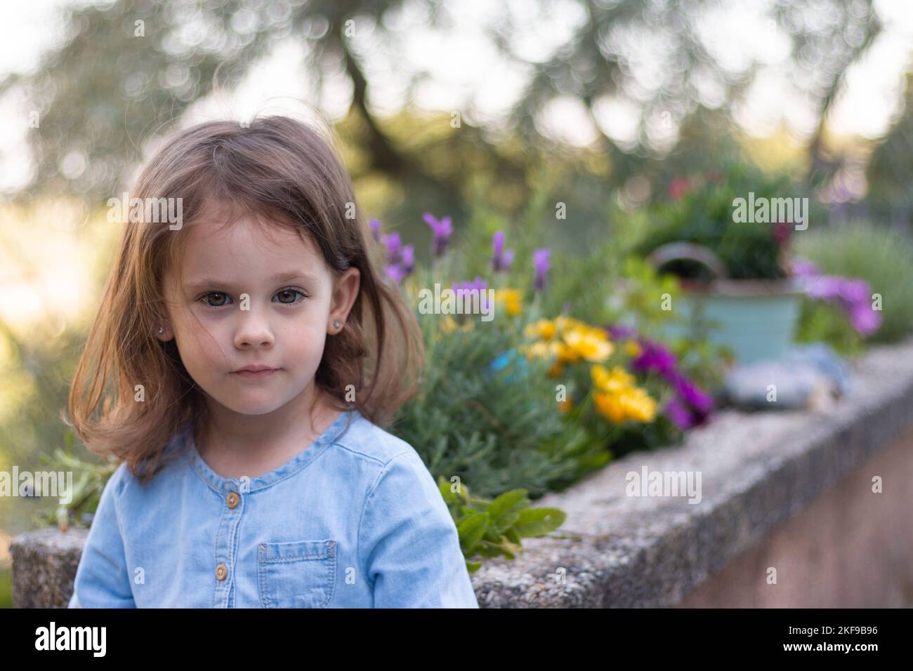 A little beautiful preschooler girl stands in a denim blue dress ...
