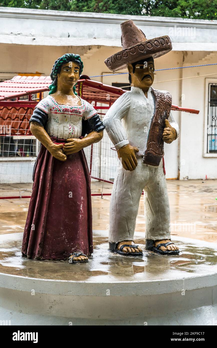 Statues of a man and woman in traditional dress in a park in the town ...