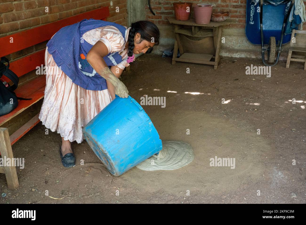 Making red clay pottery. Potter pouring out mixed clay on a sand base ...