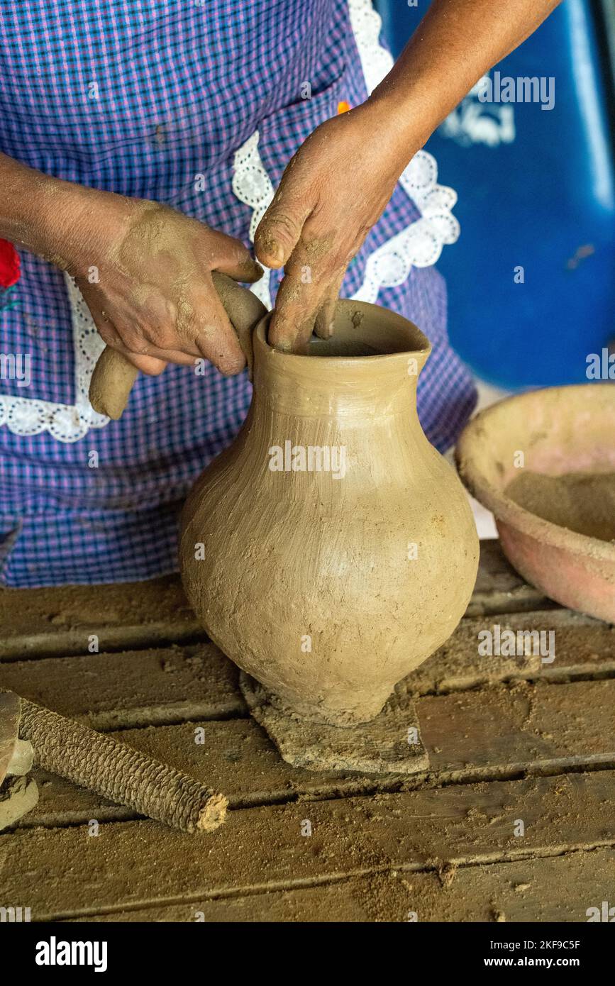 Making red clay pottery. The potter attaches a handle to make a pitcher ...
