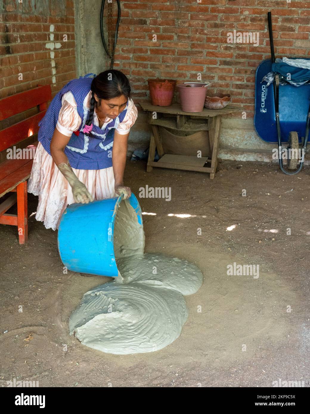 Making red clay pottery. Potter pouring out mixed clay on a sand base ...