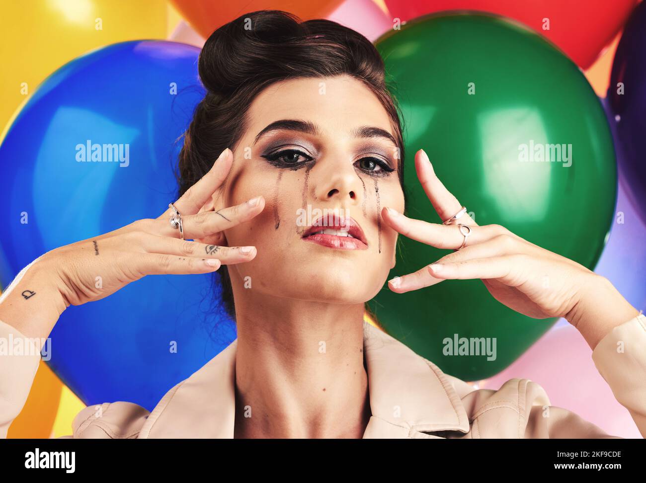 Face, beauty and makeup with a model woman in studio against a balloon background for fashion or ...