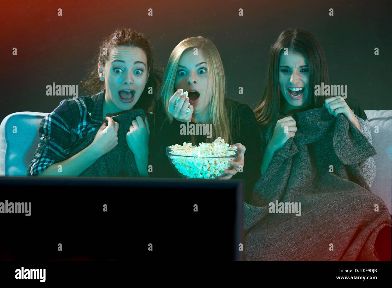 Teenage girls watching horror movie with popcorn Stock Photo - Alamy