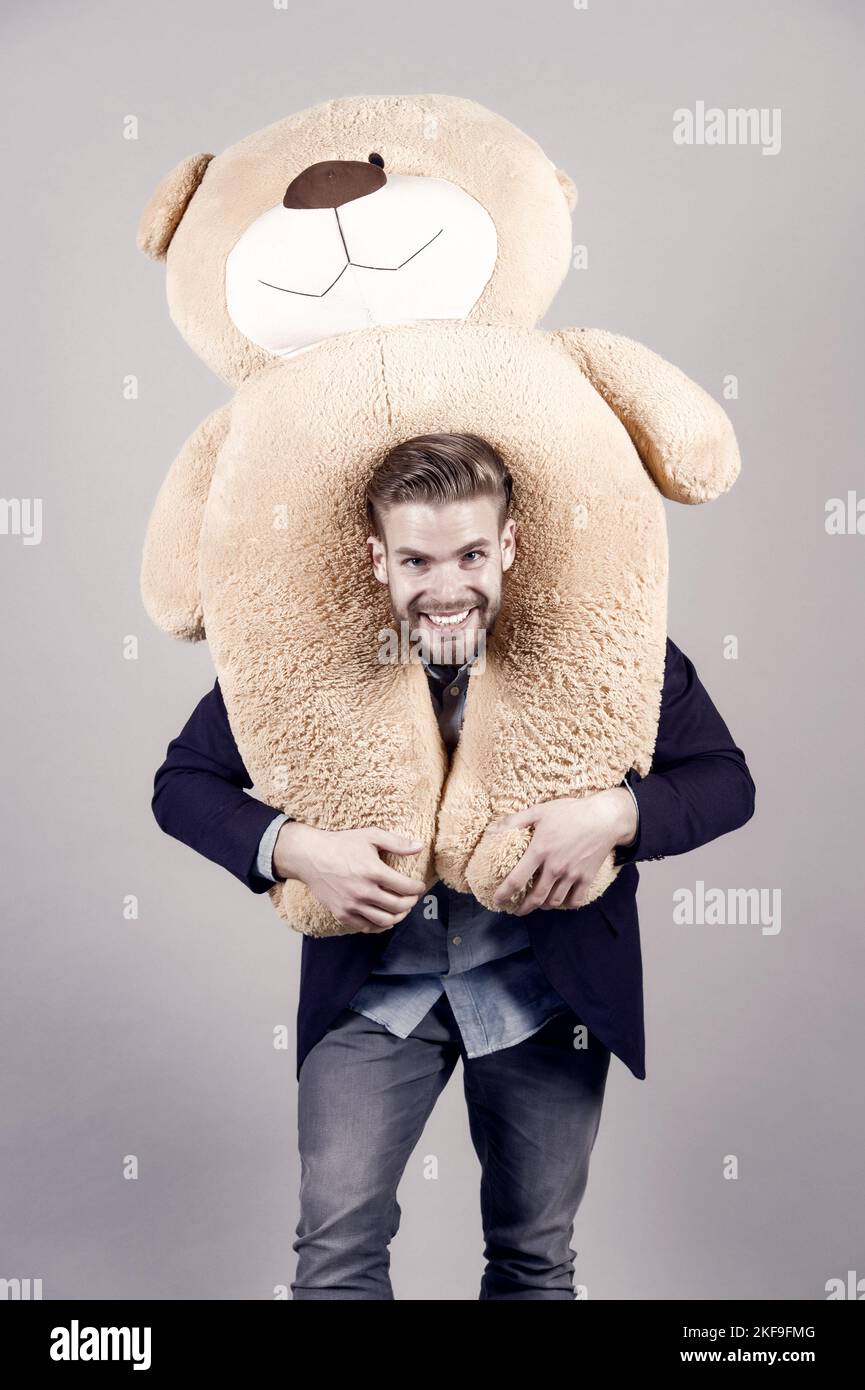 Macho smiling with big animal toy, present Stock Photo - Alamy