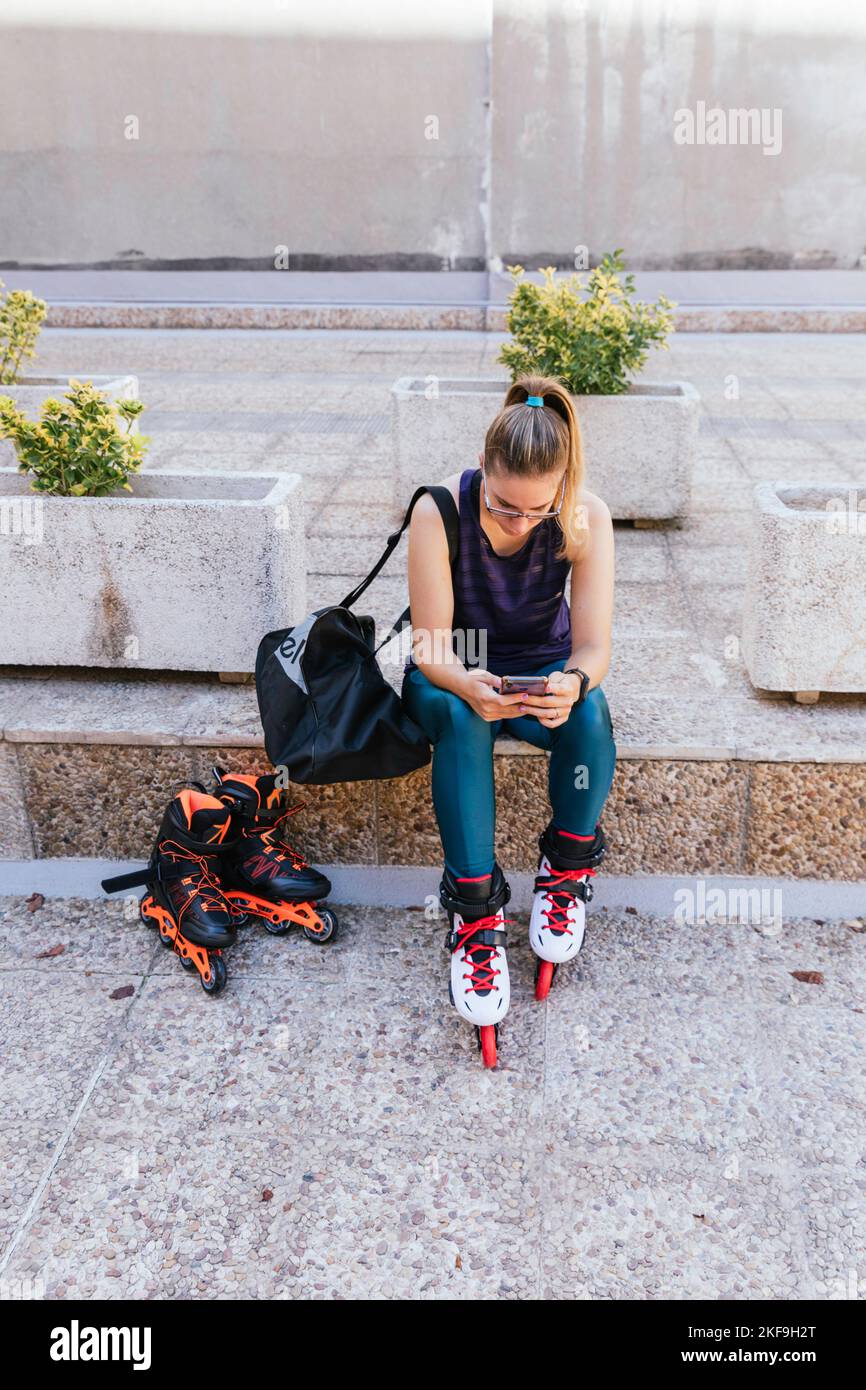 young blonde girl getting ready to go out on inline skates by looking ...