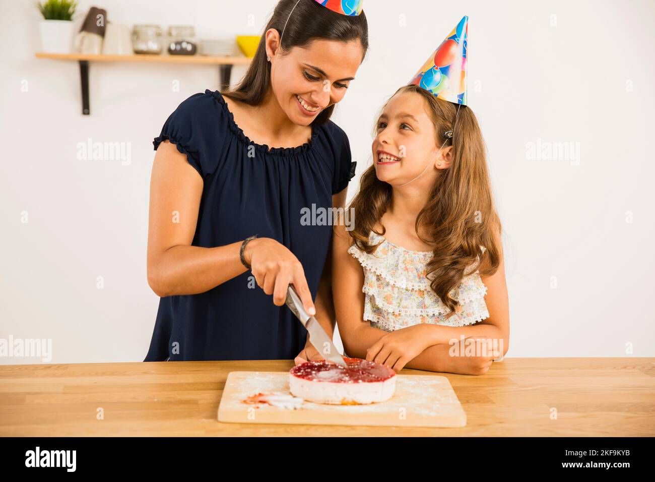 Shot of a mother and daughter cuting the cutting the birthday cake ...