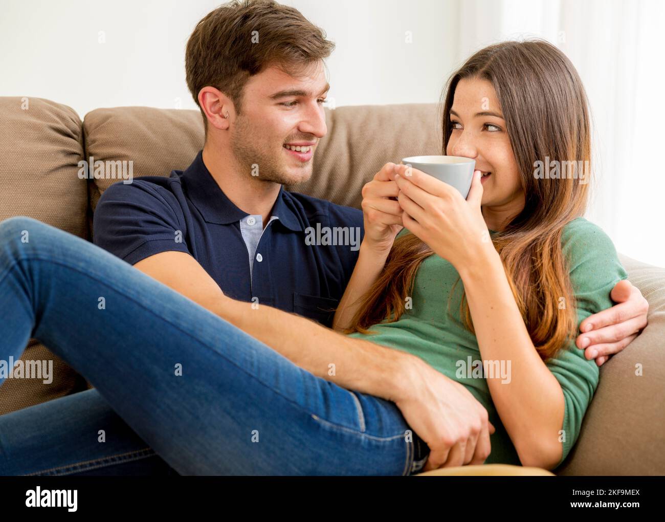 Young couple on the sofa drinking coffee Stock Photo - Alamy