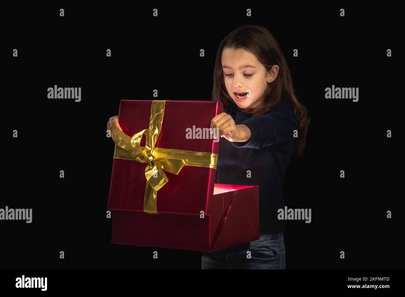 Little girl opening a present with light coming out Stock Photo - Alamy