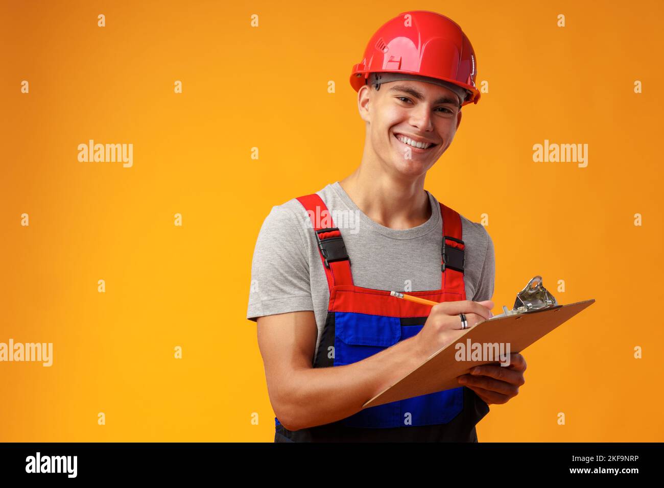 Young construction worker wearing hardhat and holding a clipboard on ...