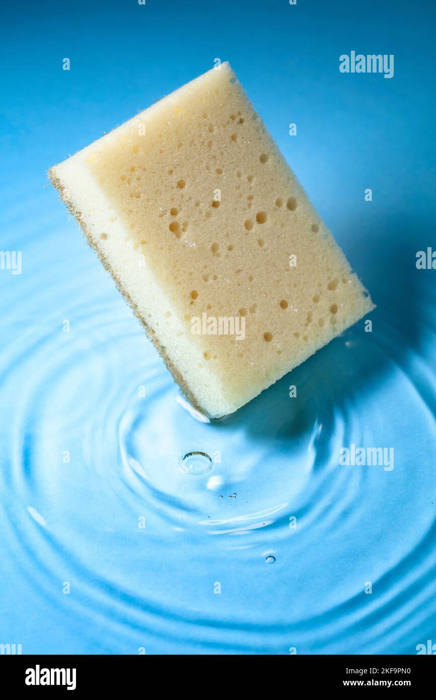 New and clean sponge falls into the water forming waves. Clean concept ...