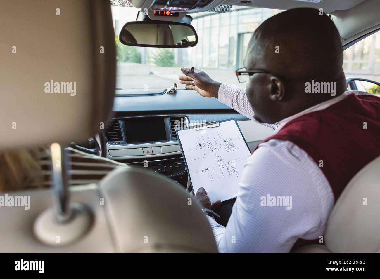 Driving school concept. A car instructor teaches a young woman how to ...