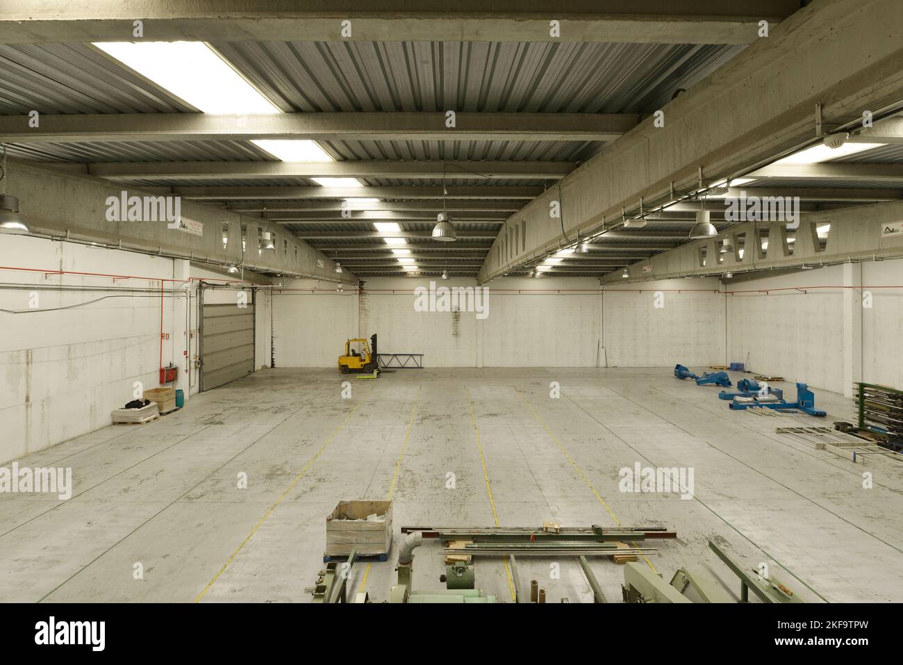A large empty industrial warehouse with concrete floors and skylights ...