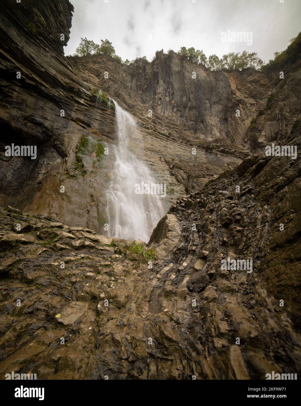 High small waterfall and steep rocks with green plants Stock Photo - Alamy