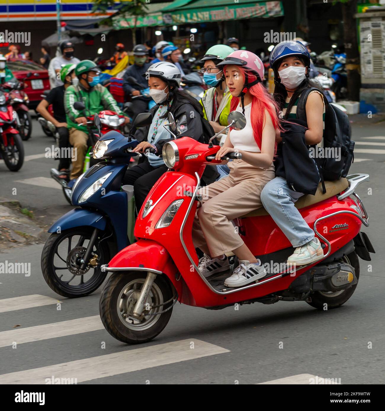 Saigon Street Life. Girl with pink hair plus her friend ride a red ...