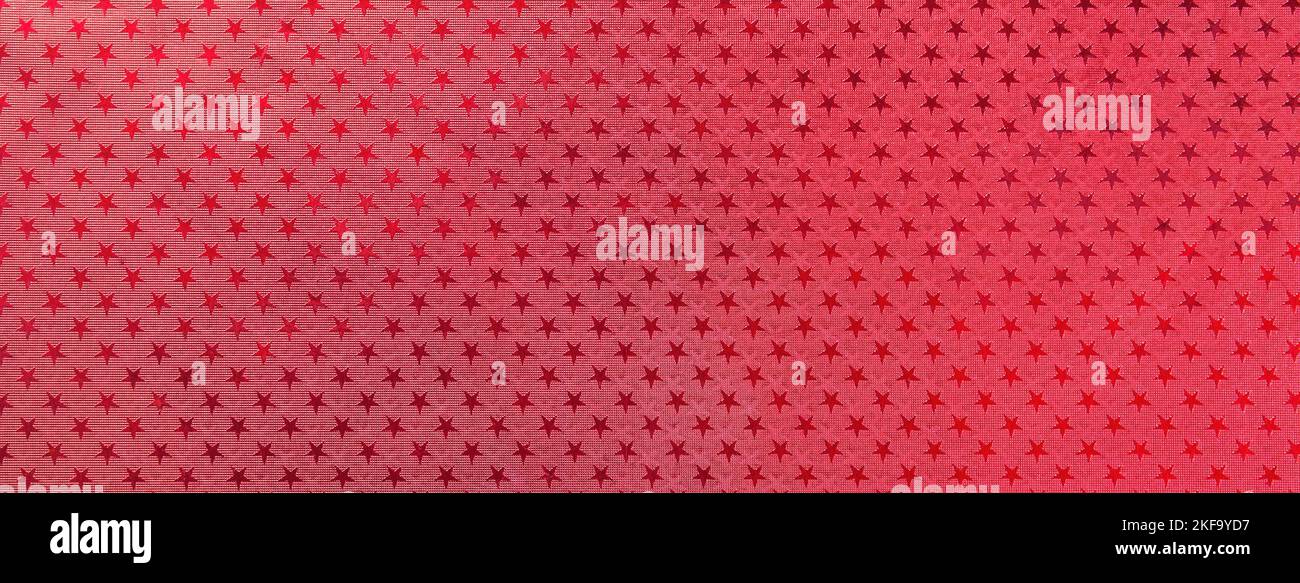 Red background from metal foil paper with a pattern of sparkling stars ...