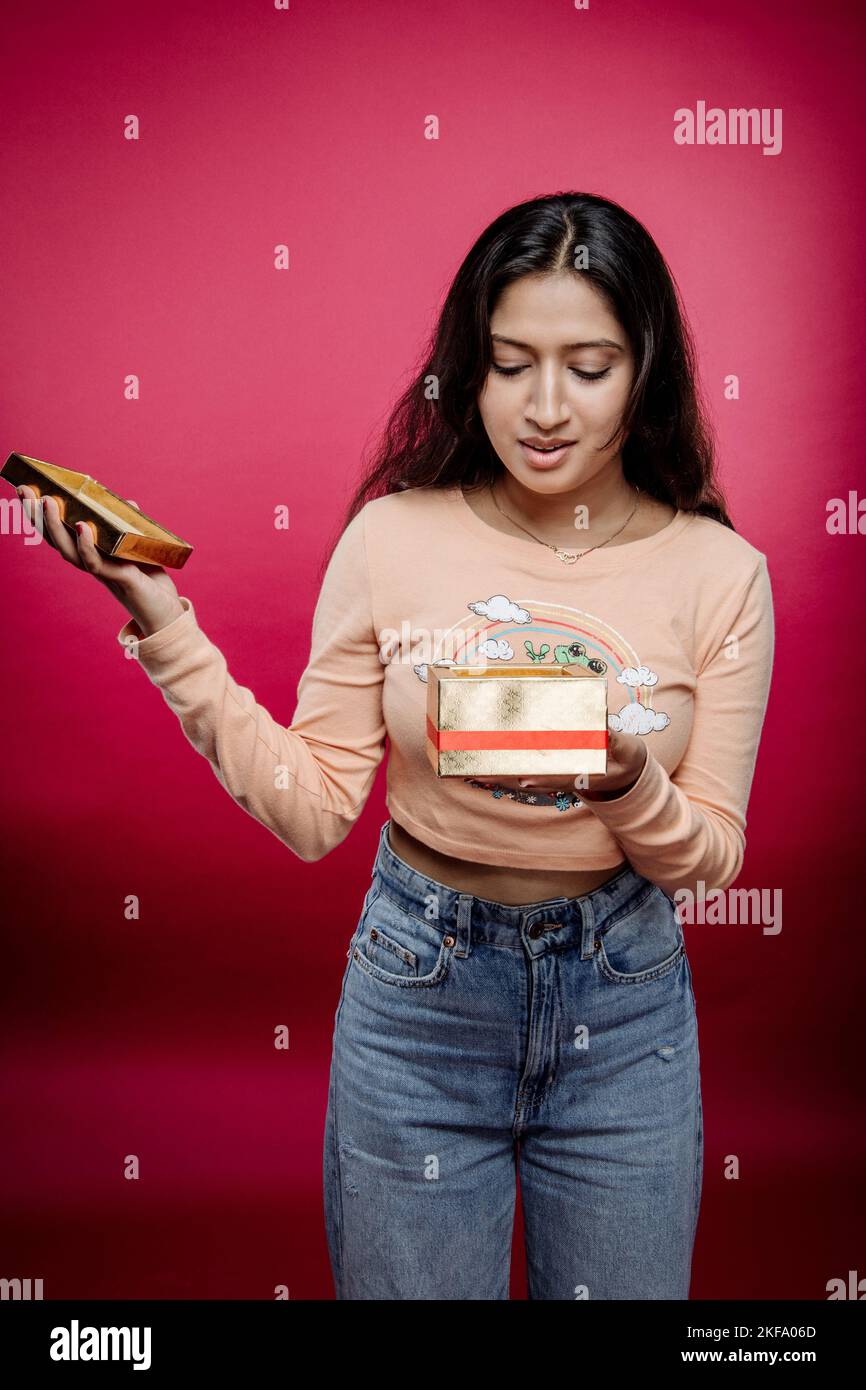 Surprised and joyful young woman receives the gift from belove and ...