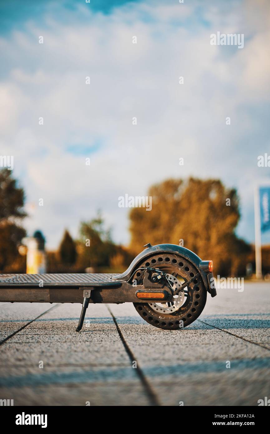 A vertical selective shot of an electric scooter's back wheel and its ...