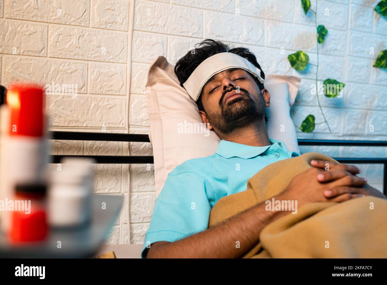 young indian sick man suffering from mild fever while sleeping at night ...