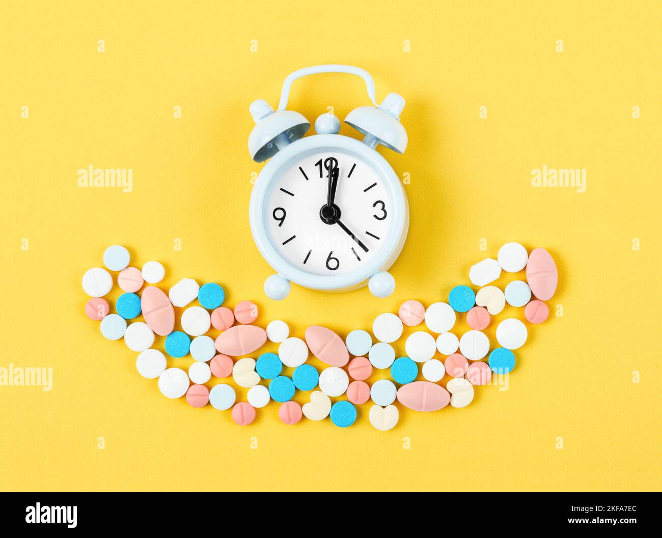 White alarm clock and many drug on a yellow background. Taking medicine ...