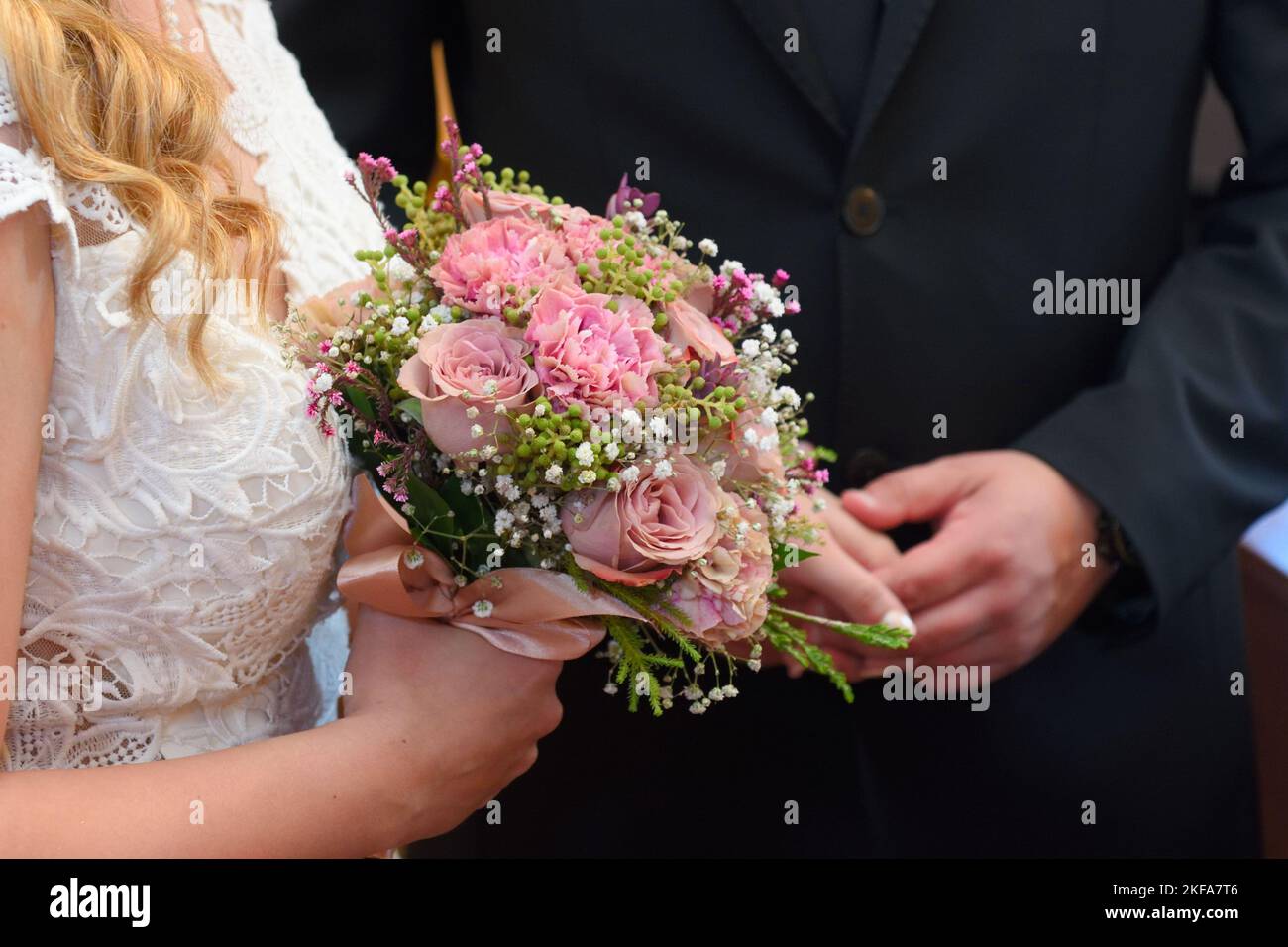 A closeup of a bride holding a flower bouquet and the groom's hand ...