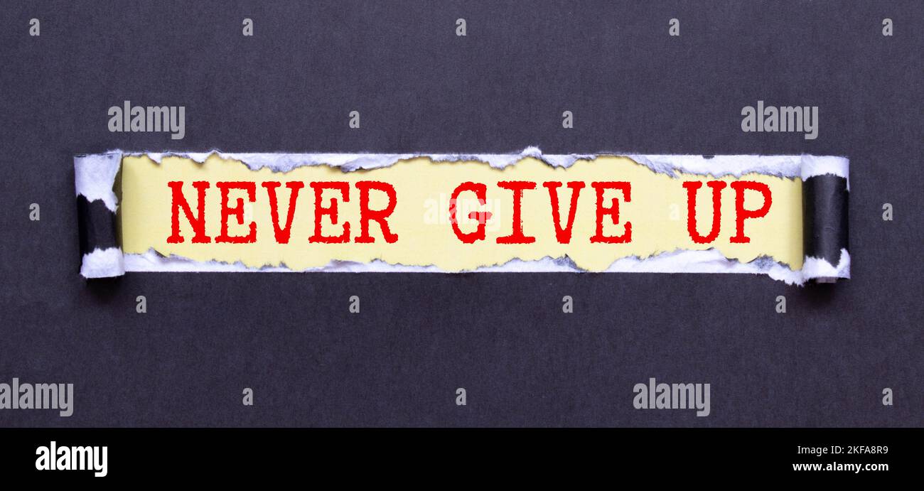 text NEVER GIVE UP on black torn paper Stock Photo - Alamy