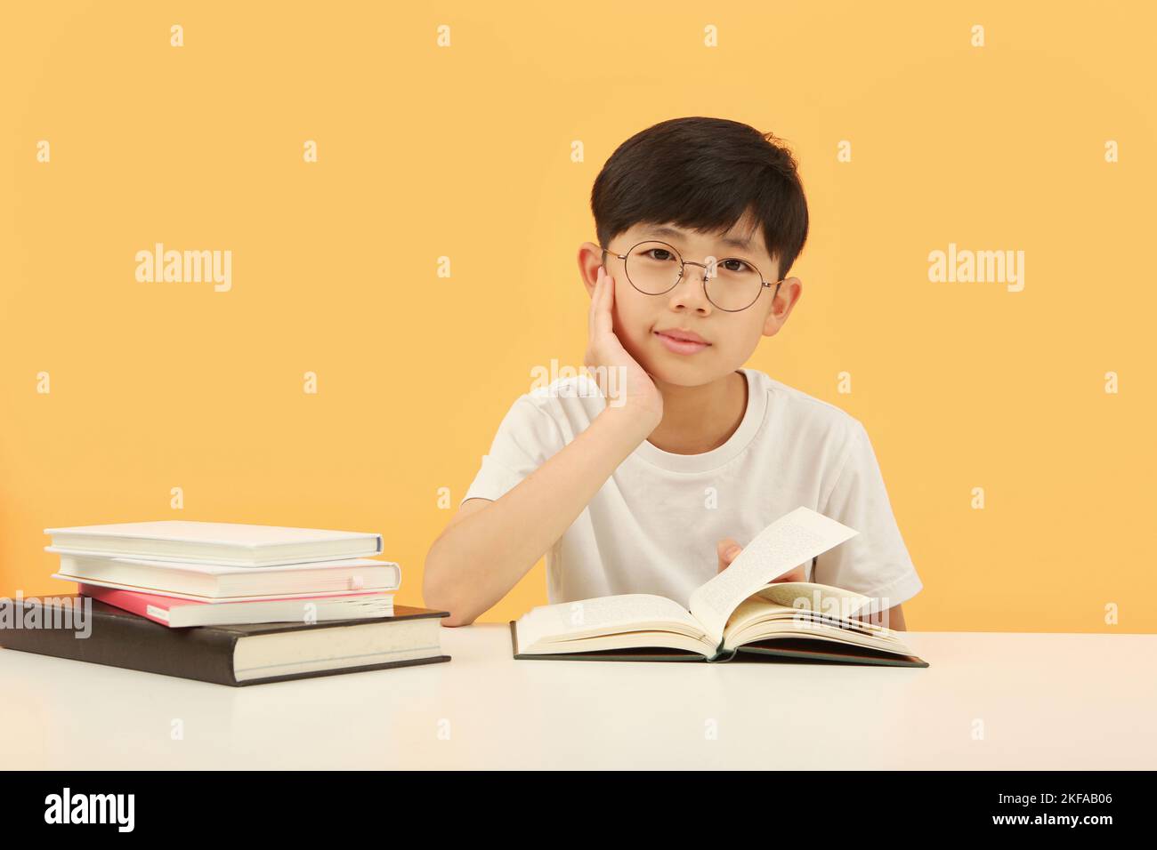 Child student concept with hand supporting chin and open book on desk ...
