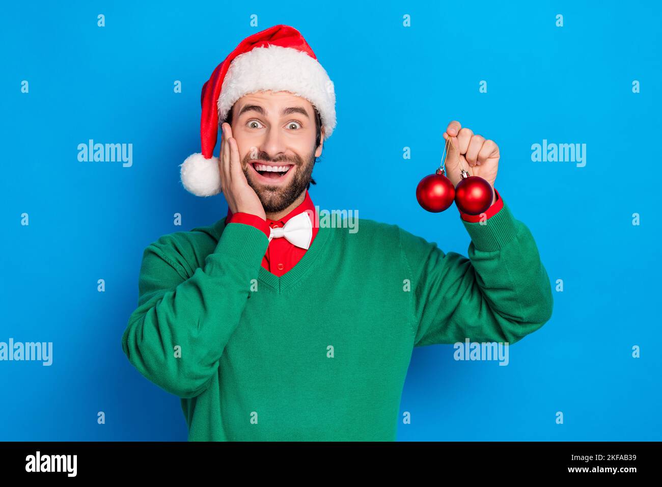 Photo of astonished cheerful man arm hold two baubles xmas tree toys ...