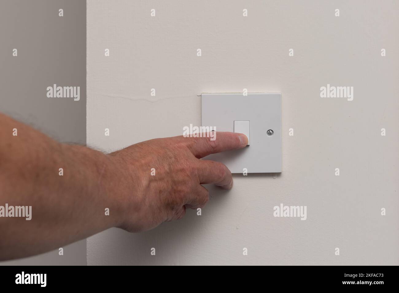 Picture of man's hand turning off the light switch to save energy. Cost ...