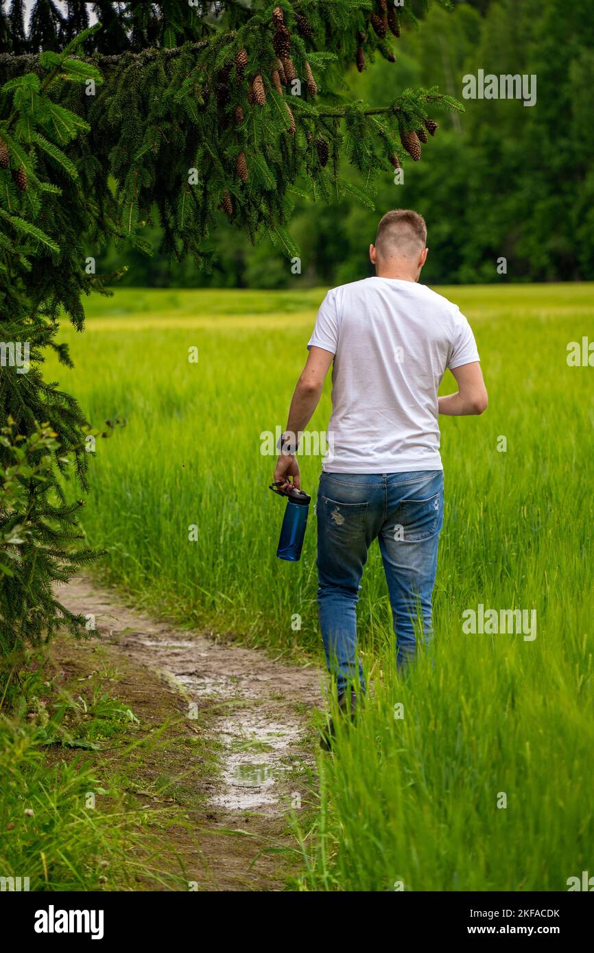 A vertical shot of a man walking in a lush green field Stock Photo - Alamy