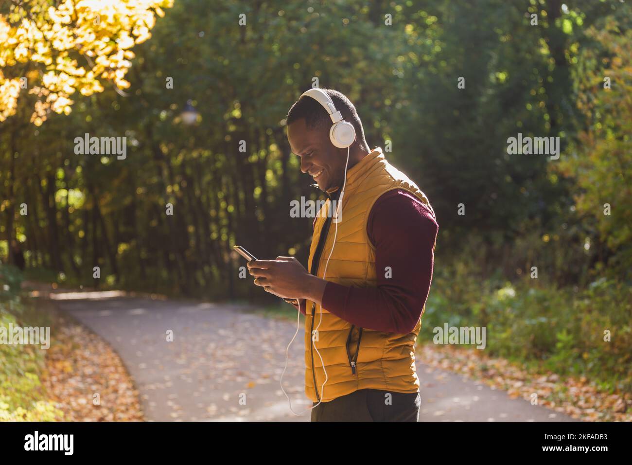 Portrait African american man listens music in autumn park copy space ...