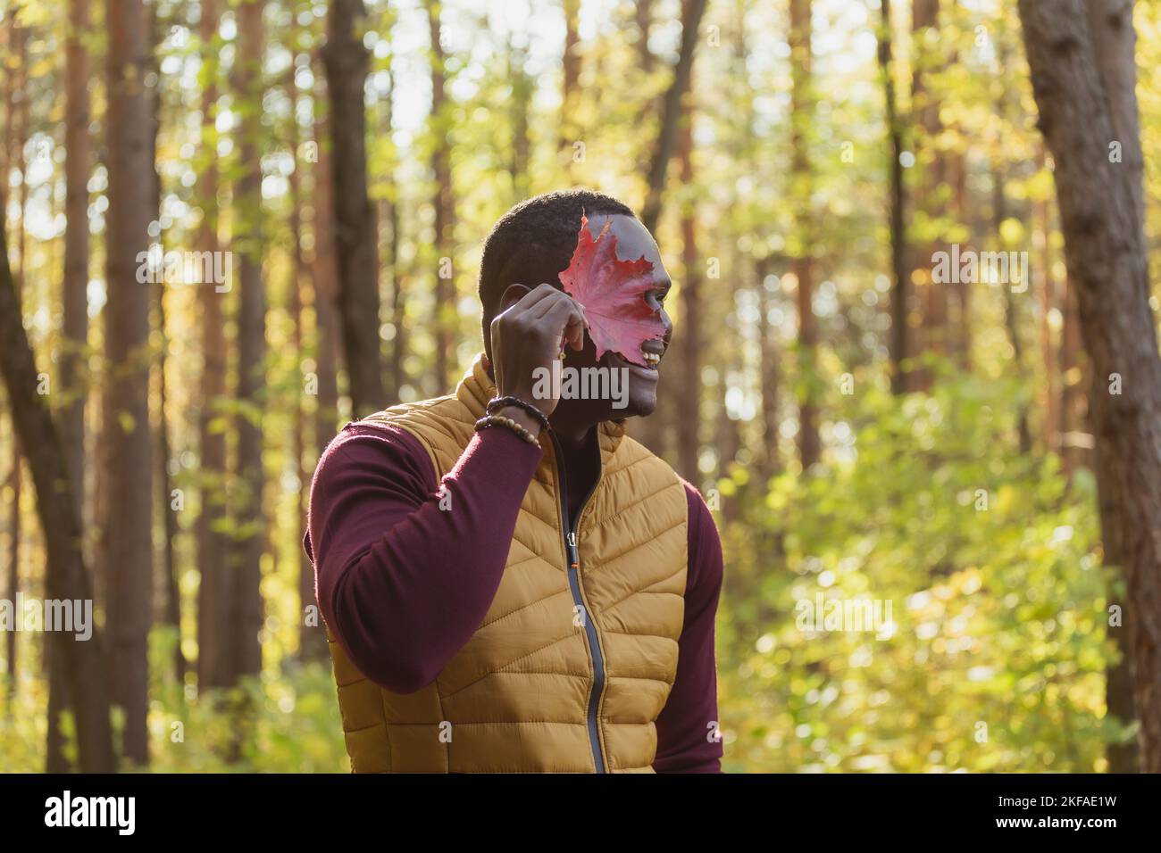Portrait of african american man covering his face with autumn maple ...