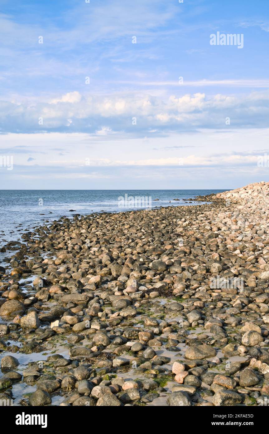 Stone beach by the sea. Danish coast on a sunny day with clouds in the ...