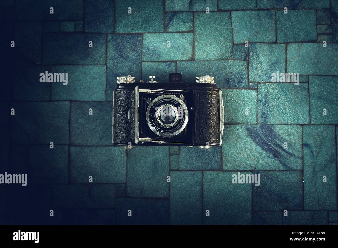 A top view of vintage camera on turquoise and blue old bathroom tiles ...