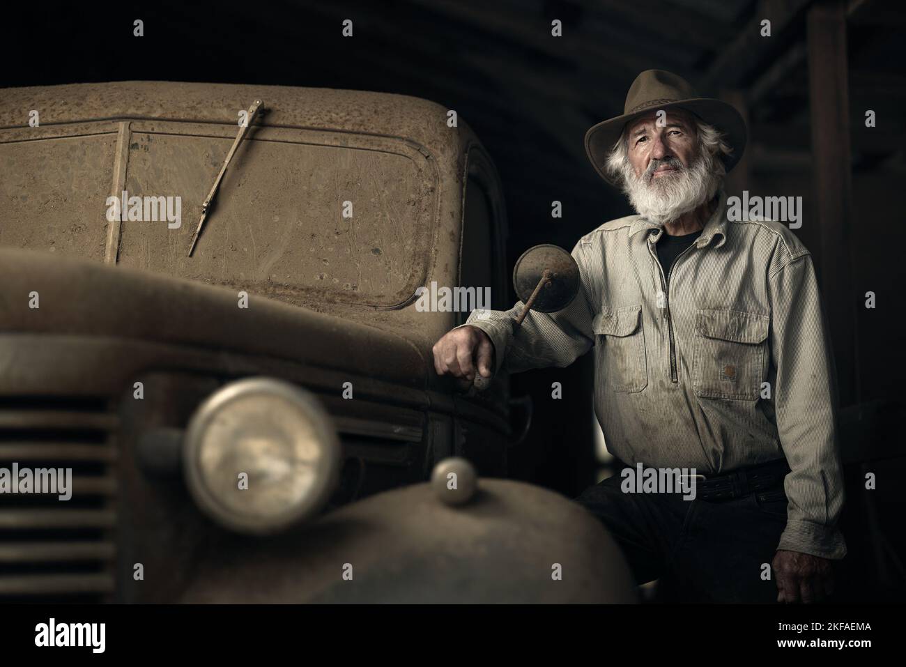 An old grandpa rancher next to his 1940 Chevrolet truck in a garage ...