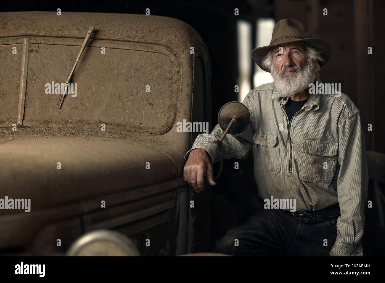 An old grandpa rancher next to his 1940 Chevrolet truck in a garage ...